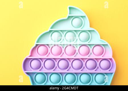Pop it toy silicone on a yellow background. Anti-stress toy, a trend in ...