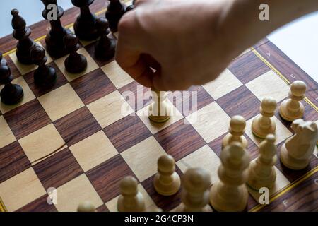 person's hand making a move in a chess game, thinking on a strategy ...