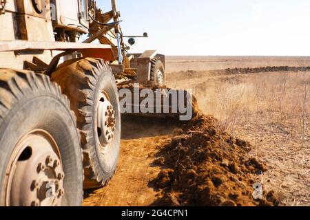 close up grader scoop dig the dirt on summer day, making a parapet ...