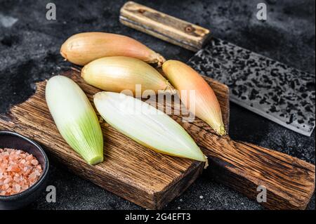 Fresh Raw cut baby shallot onion bulb on a wooden board. Black ...
