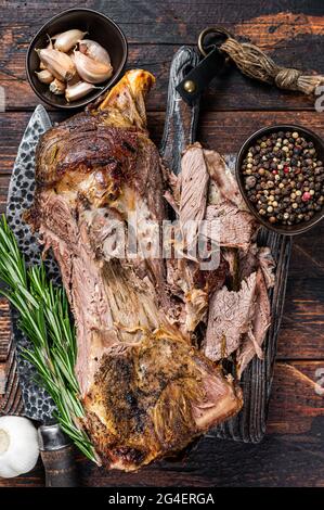 Baked lamb mutton cutting shoulder meat on a wooden board. Dark wooden ...