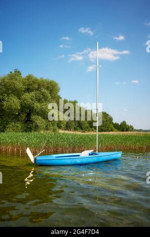 Small blue sailboat moored by reeds, Drawsko Lake, Poland Stock Photo ...