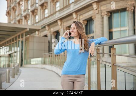 Cheerful lady smiling while standing alone with her smartphone Stock ...