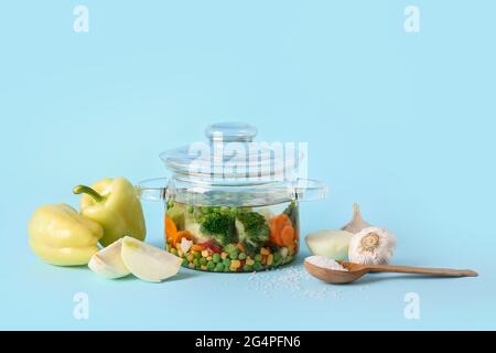 Stylish cooking pot with tasty soup and ingredients on color background ...