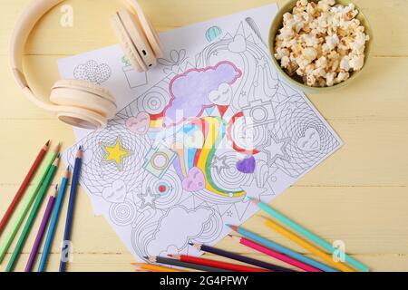Composition with coloring picture, pencils and popcorn on color wooden ...