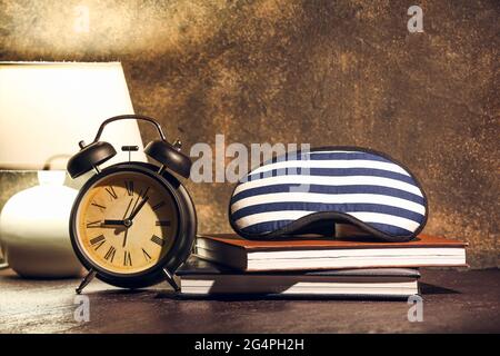 Stylish sleeping mask and alarm clock on table in bedroom Stock Photo ...
