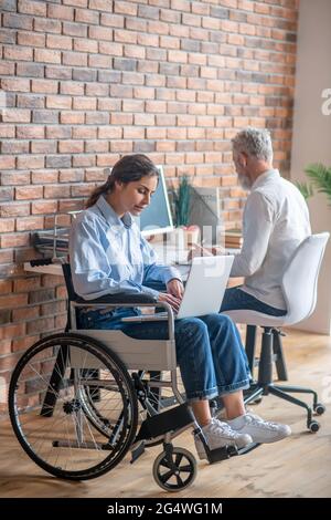 Handicapped young woman working with her colleague in the office Stock ...