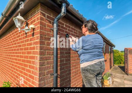Woman fixing outside lights on an external wall Stock Photo - Alamy