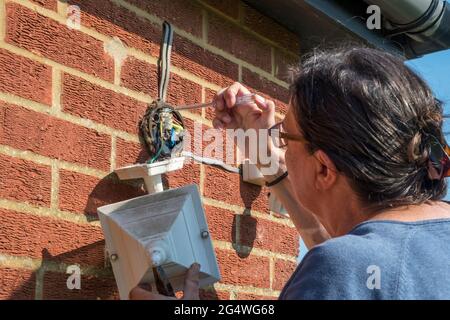 Woman fixing outside lights on an external wall Stock Photo - Alamy
