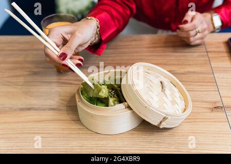 Young woman holding bamboo chopsticks near mouth and pouting lips ...