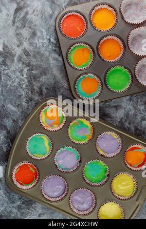 Unbaked rainbow cupcakes on oven tray. Top view Stock Photo - Alamy