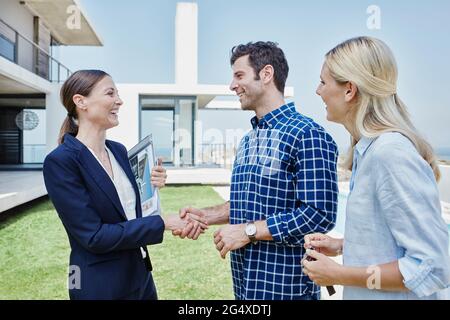 Male real estate agent with handshake smiling in white real estate room ...