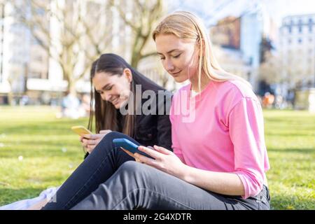 Female friends using their mobile phone together Stock Photo - Alamy