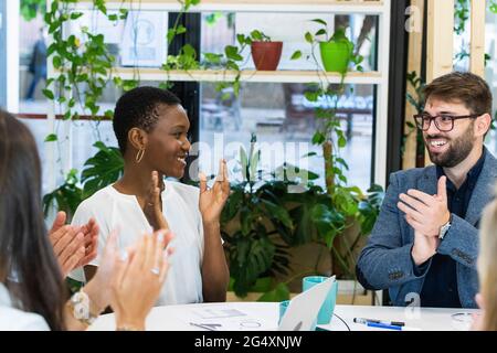 Male and female professionals clapping during birthday celebration at ...