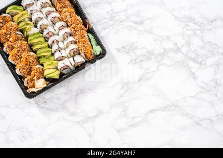 Flat lay. Pre-packaged variety of sushi and sushi rolls in a plastic ...