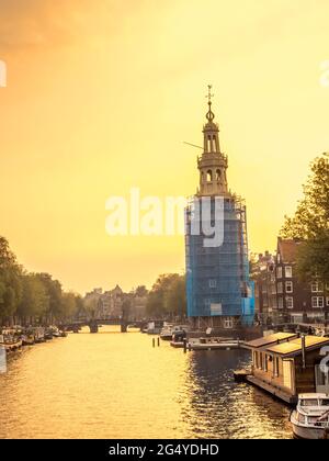 Constructed clock tower along canal in Amsterdam with evening light sky ...