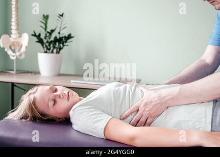 Osteopath practitioner releasing the diaphragm of a female patient, rib ...