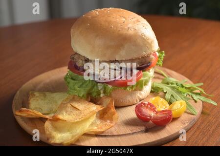 A closeup of Chicken sandwich with onion rings an a drink on the table ...