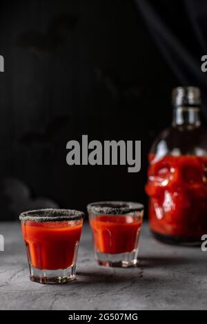 Tomato cocktail in a skull-shaped bottle and glasses. Drink for ...