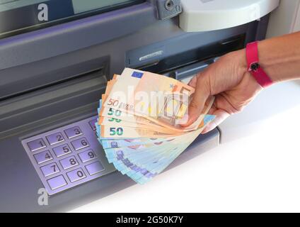 euro banknotes just withdrawn from the ATM and the hand picking them up ...