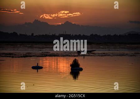 A boatman rows his boat along Dal lake during sunset in Srinagar ...