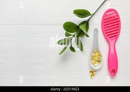 Hair brush and fish oil pills on light wooden background Stock Photo ...