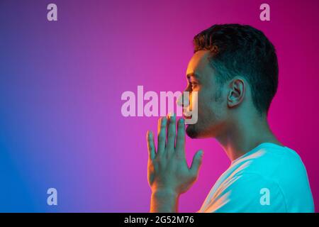 Latina young man's portrait on purple-blue studio background in neon ...