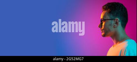 Latina young man's portrait on purple-blue studio background in neon ...