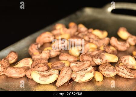 Fragrant salty roasted cashews on a bamboo plate, close-up, on a black ...