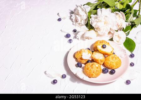 Profiteroles with blueberries. Custard cakes, Eclair, cream puff ...