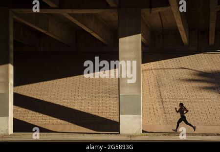 Woman jogging near brick wall in sunlight Stock Photo - Alamy