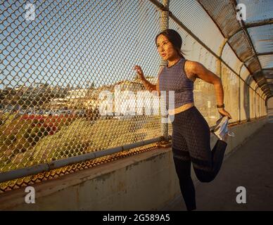 Athlete woman stretching at fence Stock Photo - Alamy