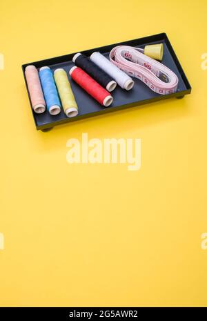 Pack of colorful sewing threads and a measuring tape on a clear ...