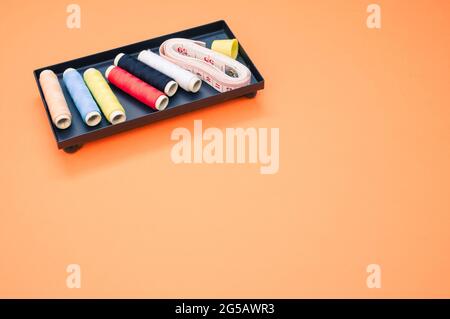 Pack of colorful sewing threads and a measuring tape on yellow ...