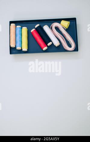 Pack of colorful sewing threads and a measuring tape on orange ...