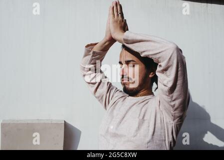 Ecuadorian young man with a mark on his forehead praying on a white ...