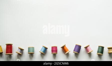 Lots of multicolored threads on old-fashioned wooden reels on a white ...