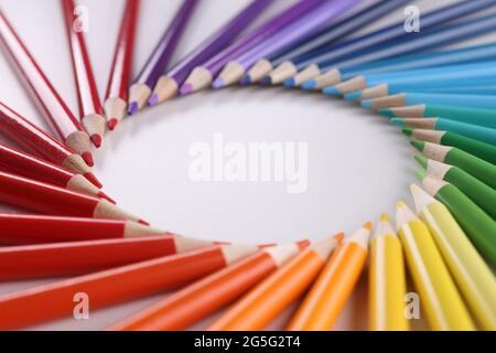 Many multi-colored wooden pencils lying in shape of circle over colors ...