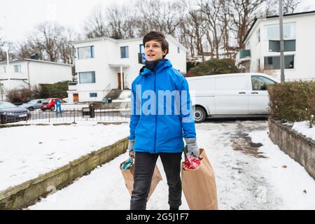 Winter delivery service. Woman carrying a big present isolated on snow ...