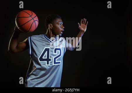 Aggressive basketball player poses with ball in studio, black ...