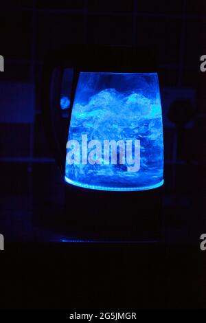 A see-through kettle boiling water, in the dark, illuminated only by a ...