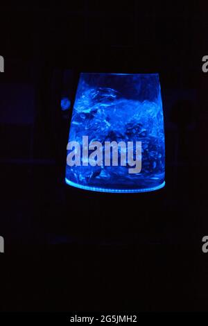 A see-through kettle boiling water, illuminated by a blue light inside ...