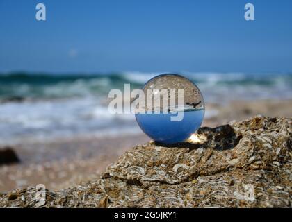 Crystal ball at a beach with the surroundings reflecting in the glass ...