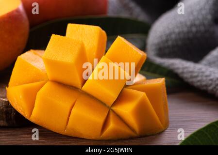 Fresh chopped mango with green leaves on bright blue color timber ...