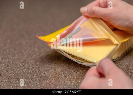 Opens a bag of sliced cheese, a woman opens a bag of cheese, pieces of ...