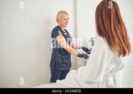 Cosmetologist showing client special medical equipment. cosmetologist ...