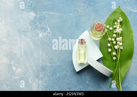 Bottles with essential oil and lily-of-the-valley flowers on color ...