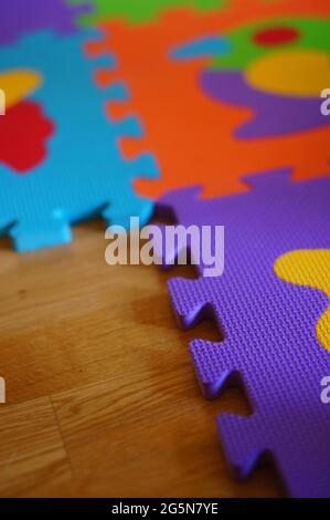 Colorful puzzle mat on wooden background Stock Photo - Alamy