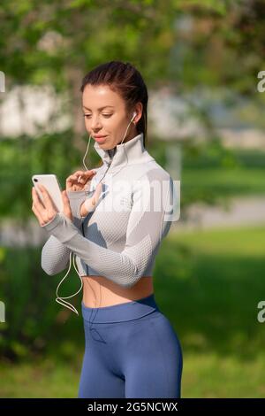 Vertical photo of woman jogging outdoors in park wearing sportswear and ...