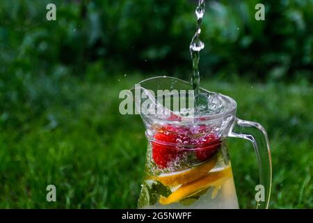 Defocus drops and jet of water pouring from plastic bottle in glass jug ...